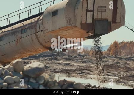 Crushed rock being ejected from the discharge chute of a multi-bucket ...