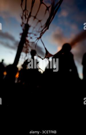 Unidentified people silhouetted through red ribbon fence against ...