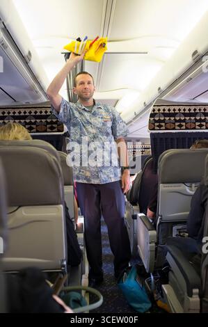 A flight attendant demonstrating life vest to passengers in an airplane ...