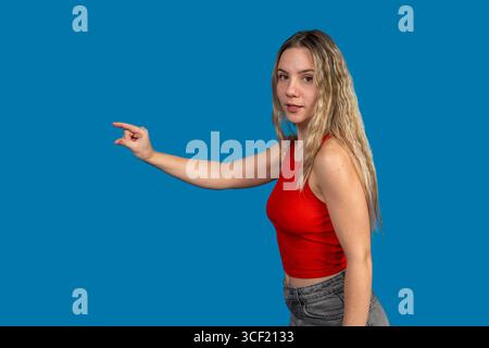 Woman pointing to the side on blue background Stock Photo - Alamy
