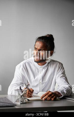 Handsome and fashionable indian man in black sitting at room, smoking ...
