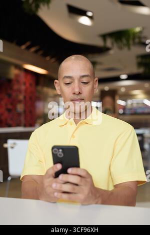 Portrait of a mature bald Italian man sitting indoors at a modern food ...