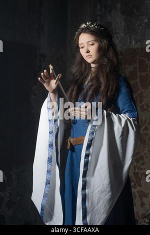 Fantasy warrior maiden in blue medieval dress, gripping dagger with ...