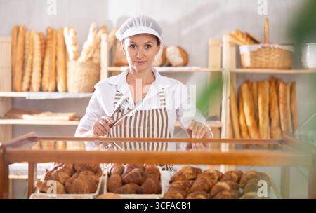 Female baker places fresh croissants on display in shop Stock Photo - Alamy