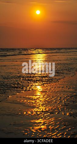 Serene golden hour sunset reflecting on tranquil water with silhouetted ...