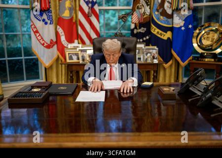 President Donald Trump works in the Oval Office of the White House on ...