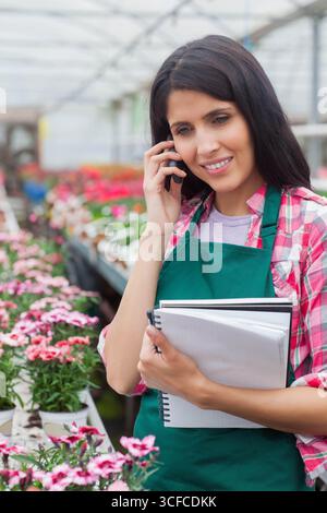 Modern greenhouse with rows of green potted plants and hanging flower ...