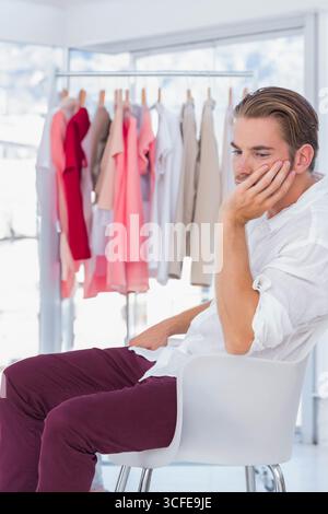 thoughtful man holding hand near face and writing in notebook near ...