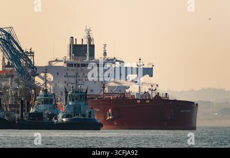 Oil tanker ship moored at marine terminal with fuel storage tanks and ...