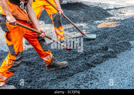 workers repair the road. bright orange traffic cones standing in a row ...