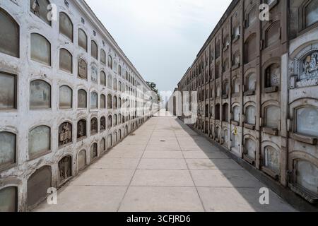 Symmetrical walkway between historic mausoleum walls filled with burial ...