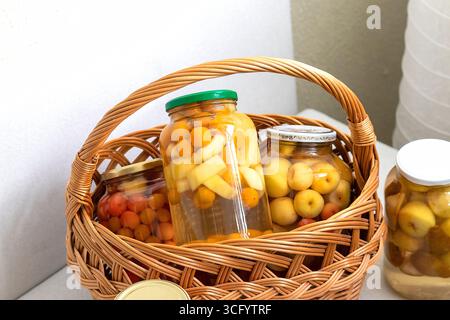 Canned compote in jars of various fruits and berries in the wicker ...