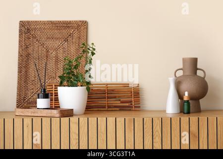 Aroma diffuser, wicker decorations and houseplant on chest of drawers ...