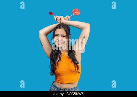 Young brunette teenager holding heart draw smiling happy pointing with ...