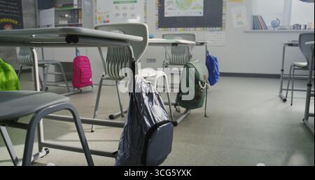 Interior of empty classroom with desks and backpacks on chairs Stock ...