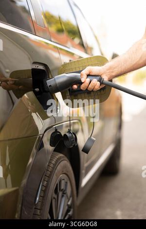 Close up of man plugging EV charger into electric vehicle outside Stock ...