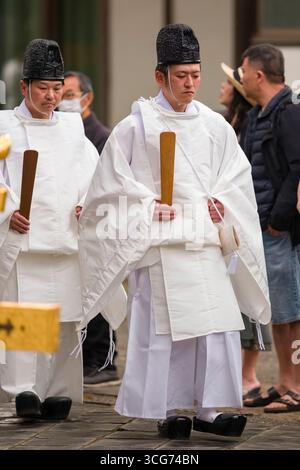 Procession of Shinto priests wearing traditional robes and hats during ...