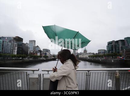A person holding an umbrella crosses the Sean O'Casey bridge a wet and ...