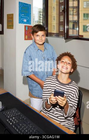 Two boys with a smartphone in their hands having fun on the grass Stock ...
