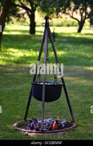 Cooking pot hanging over a campfire on a tripod at a tourist camp, a ...