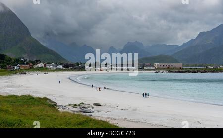 Tourist enjoying ramberg beach in lofoten islands, norway, on a cloudy ...
