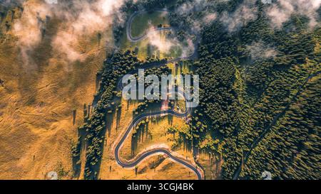 Cinematic aerial view of winding alpine road with sweeping curves ...
