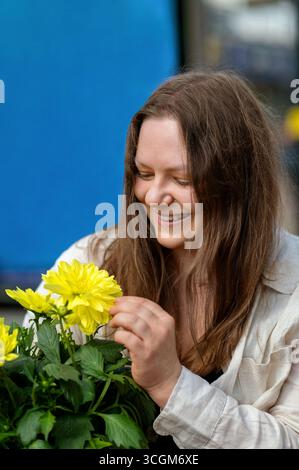 Portrait of happy female customer choosing clothes in clothing store ...