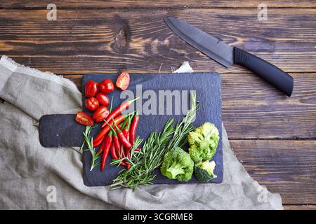 Wooden cutting board with broccoli and tomatoes on black background ...