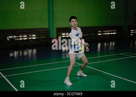 young man taking back shuttlecock in badminton court Stock Photo - Alamy