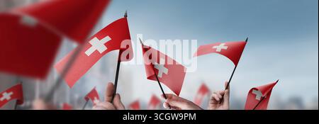 Switzerland flags in their hands on a blurred urban background Stock ...