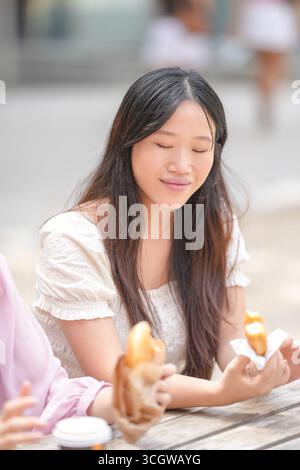 Young Japanese woman eating a donut Stock Photo - Alamy