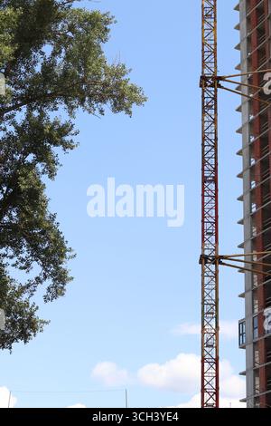 Tall construction crane near high-rise buildings under a cloudy sky in ...