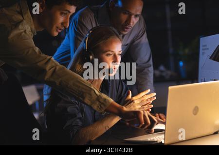 Team collaborating at night, focused on laptop screen, discussing ...