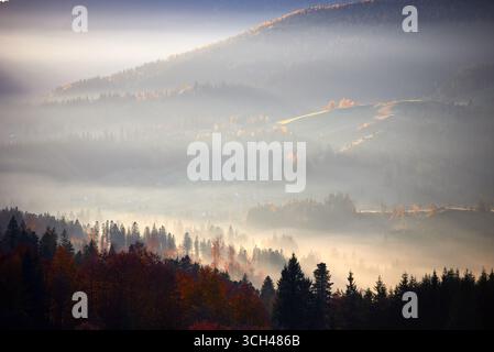 Misty mountain slope with sunlight breaking through clouds against a ...