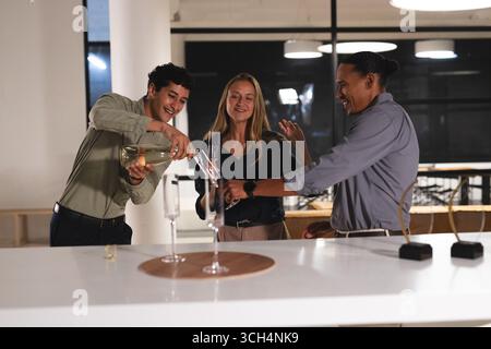 Colleagues celebrating success, pouring champagne and laughing in ...