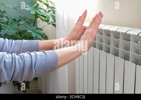 Woman touching warm radiator with both hands Stock Photo - Alamy