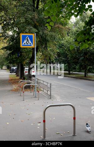 Pedestrian crossing sign on quiet green city street in urban spring ...