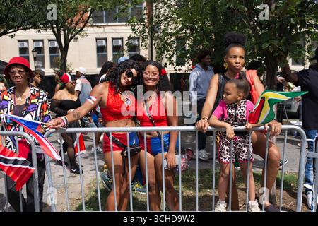 People stand behind a metal barrier, holding Israeli and American flags ...