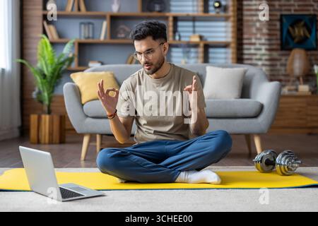 Online yoga practice. Mature asian man doing butterfly asana on sports ...