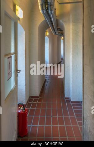 Bright corridor with white walls and tiled floor with a doorway to the ...