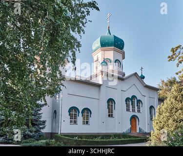 A peaceful Orthodox church with white walls and black roofs in front of ...