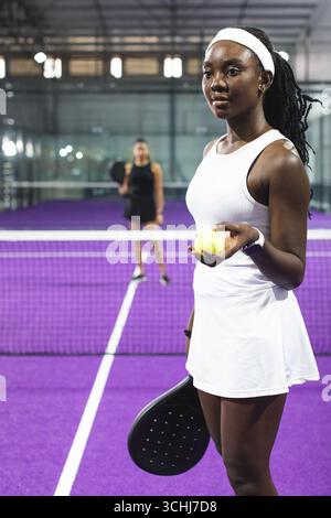 Athletic woman playing paddle on a sun court in summer. Tennis players ...