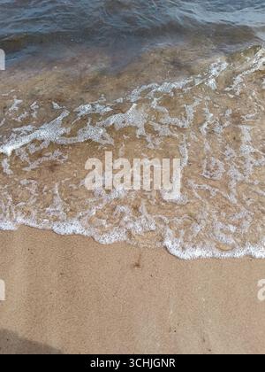 Gentle ocean waves lapping against a sandy beach, creating a smooth ...