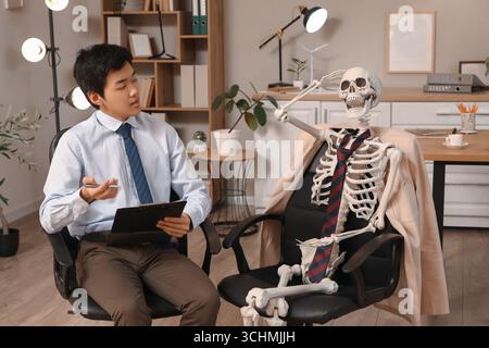 Skeleton businessman working in office Stock Photo - Alamy