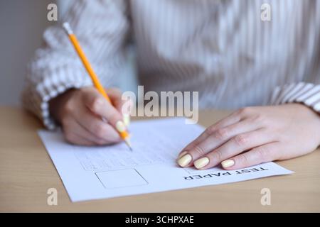 Student filling out multiple choice test at table in class, closeup ...