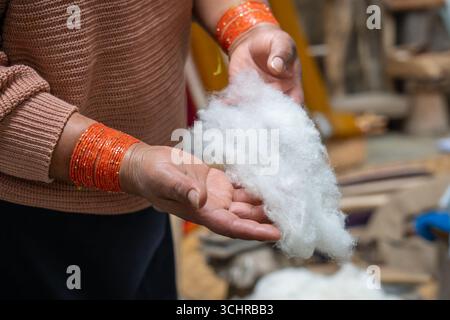 A woman shows wool fibers after carding in the Tahuantinsuyo Weaving ...