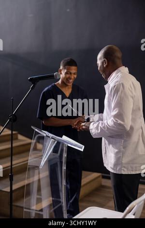Man receiving award on stage while audience clapping in modern office ...