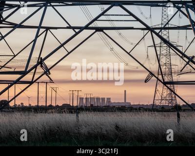 A silhouette view of the electricity pylons by a rural road against ...