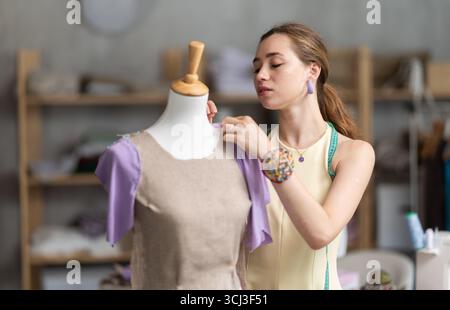 Female tailor sews new dress on a mannequin in sewing studio Stock ...