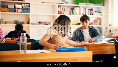 Writing, assessment and quiz with girl in classroom for test, child ...